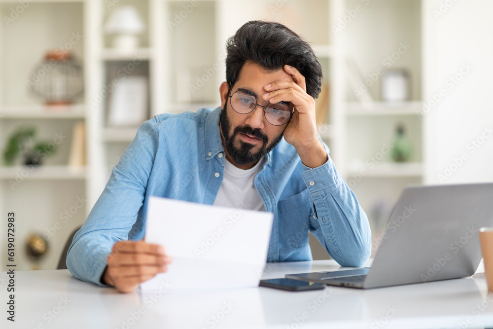 Upset Young Indian Man Sitting At Desk With Laptop And Checking ...