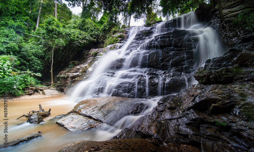 Beautiful waterfall in green tropical forest. View of the falling water ...