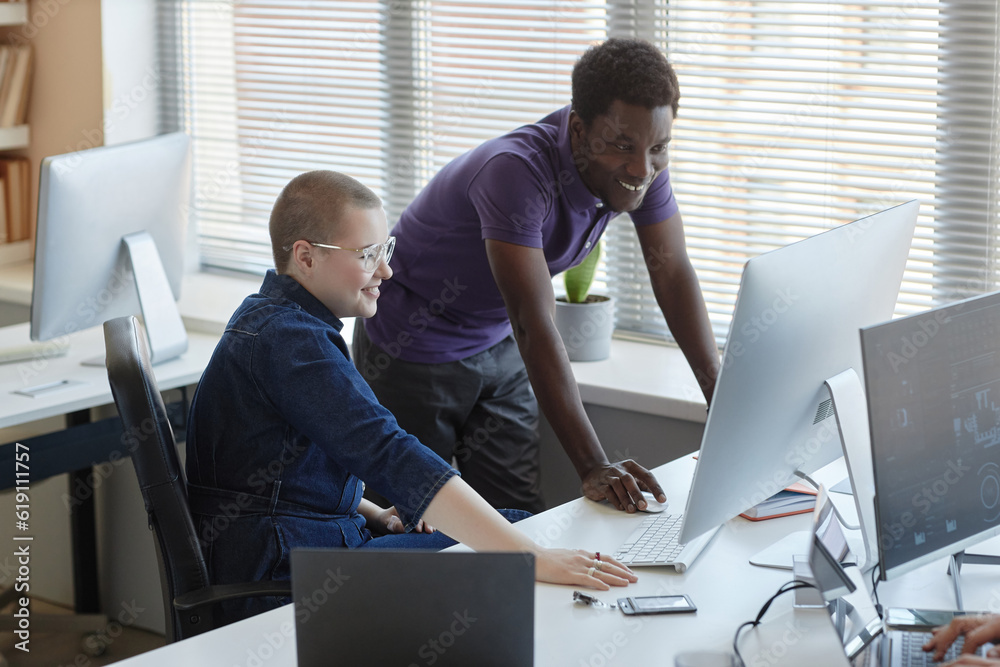 Two happy young intercultural cyber security managers looking at screen of computer while ...