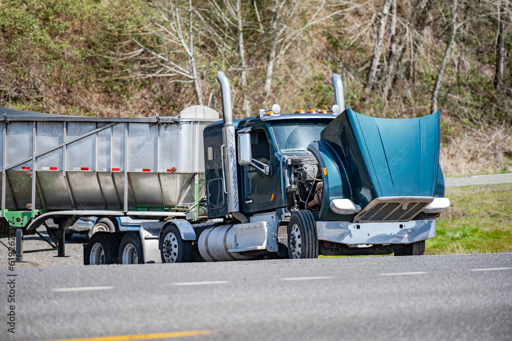Dark green broken big rig day cab semi truck with open hood and bulk ...