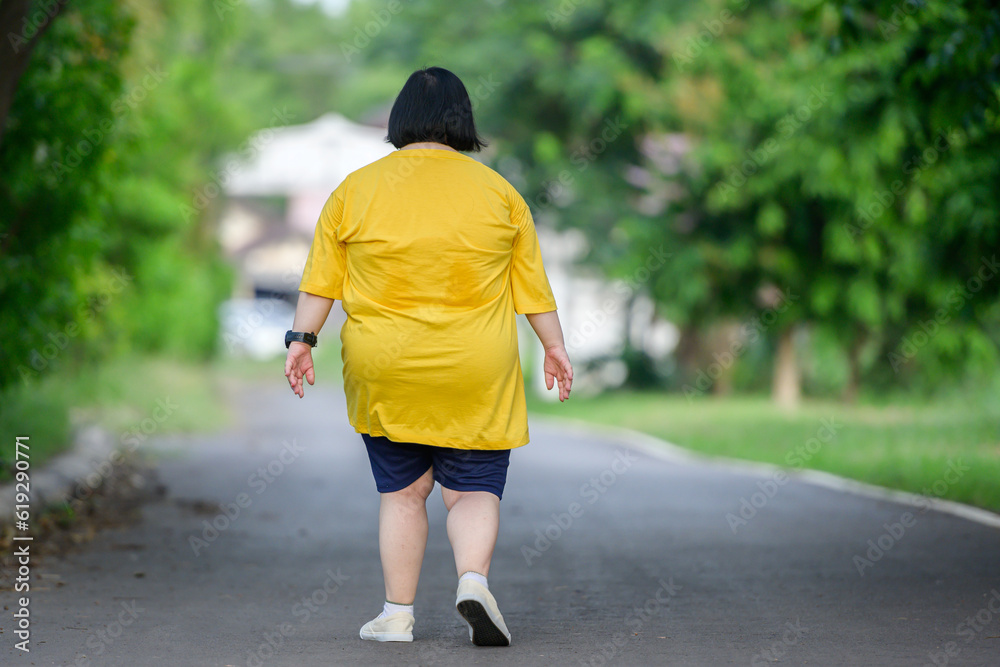 back view fat asian girl exercising By walking to burn fat and jogging ...