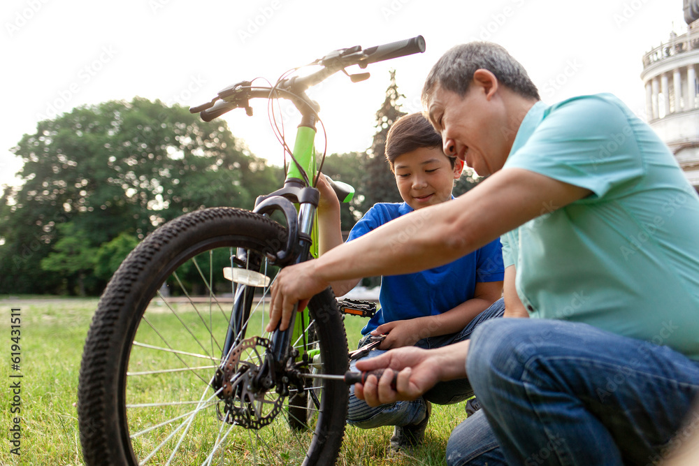 asian father helping son to repair bike with tools, korean little boy watching dad fix broken ...