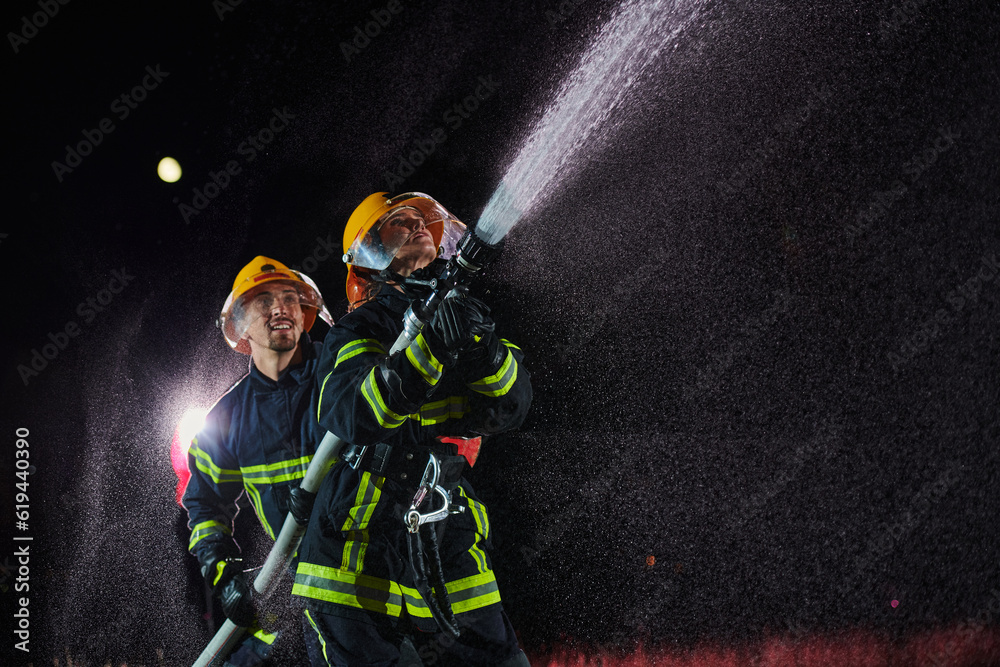 Firefighters using a water hose to eliminate a fire hazard. Team of ...