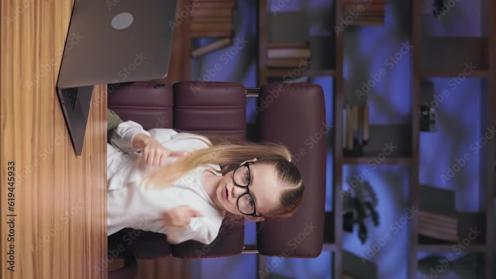Vertical video of active kid having fun at office desk with remote ...
