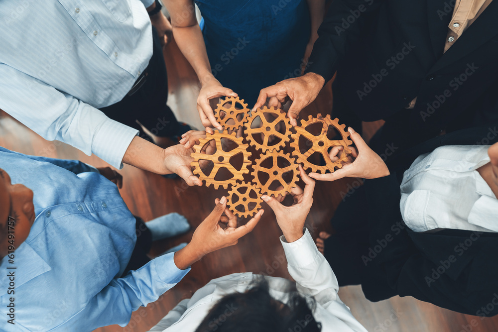 Office worker holding cog wheel as unity and teamwork in corporate ...