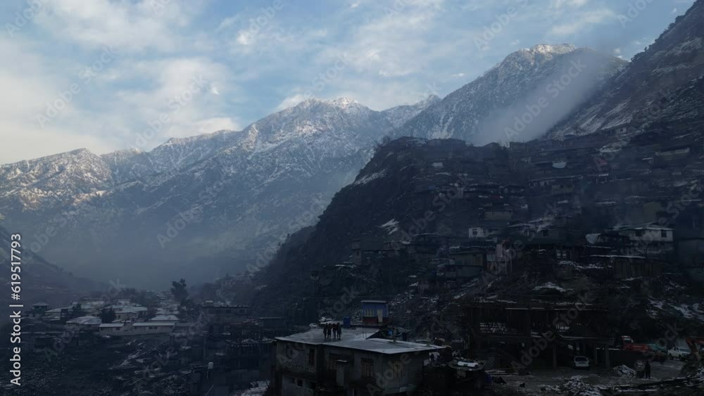 Houses built on mountain slope with clouds and huge mountains in ...