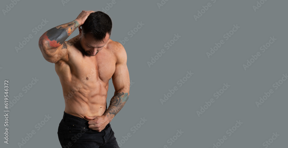 Male bodybuilder with developed body muscles, on a grey background ...
