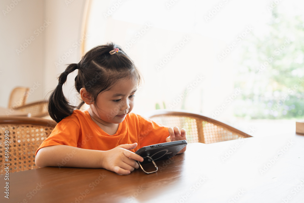 Asian child girl looking using and touch mobile phone screen. Baby ...