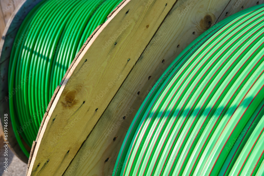 Wooden rolls of green colored industrial tube cable for underground ...