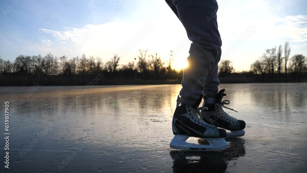 Male legs in figure skates sliding on lake covered by ice. Man enjoying ...