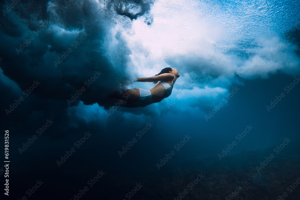 Woman swim underwater with breaking wave with foam in transparent ocean ...