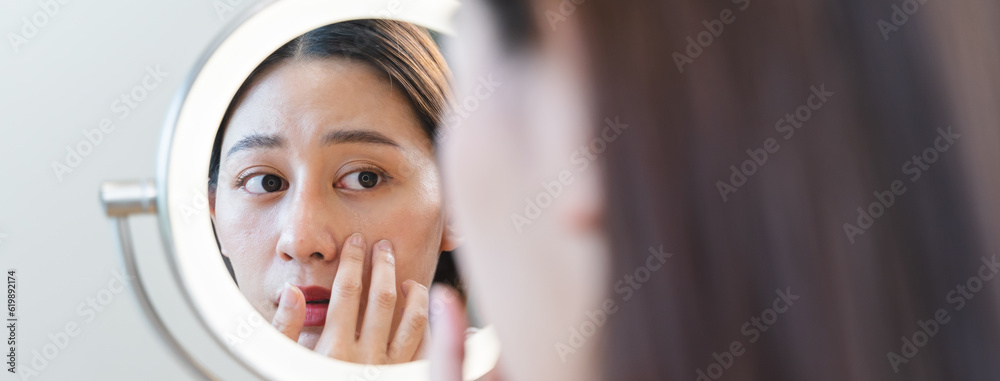 Young Asian woman looking in the mirror worried about the crack face ...