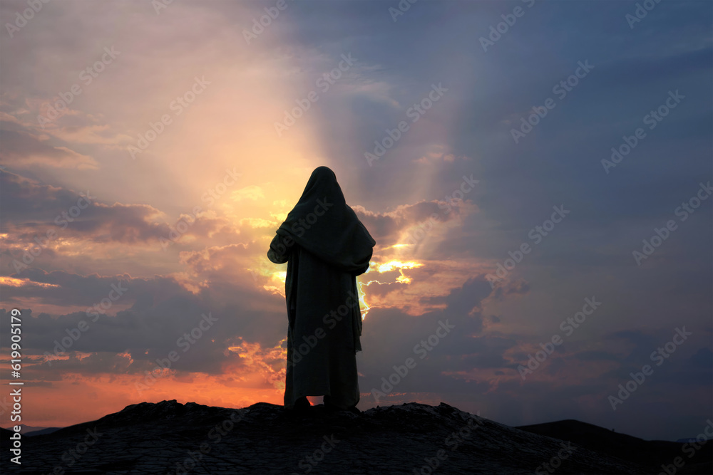 Jesus praying alone on a hill at sunset with rays. Biblical concept ...
