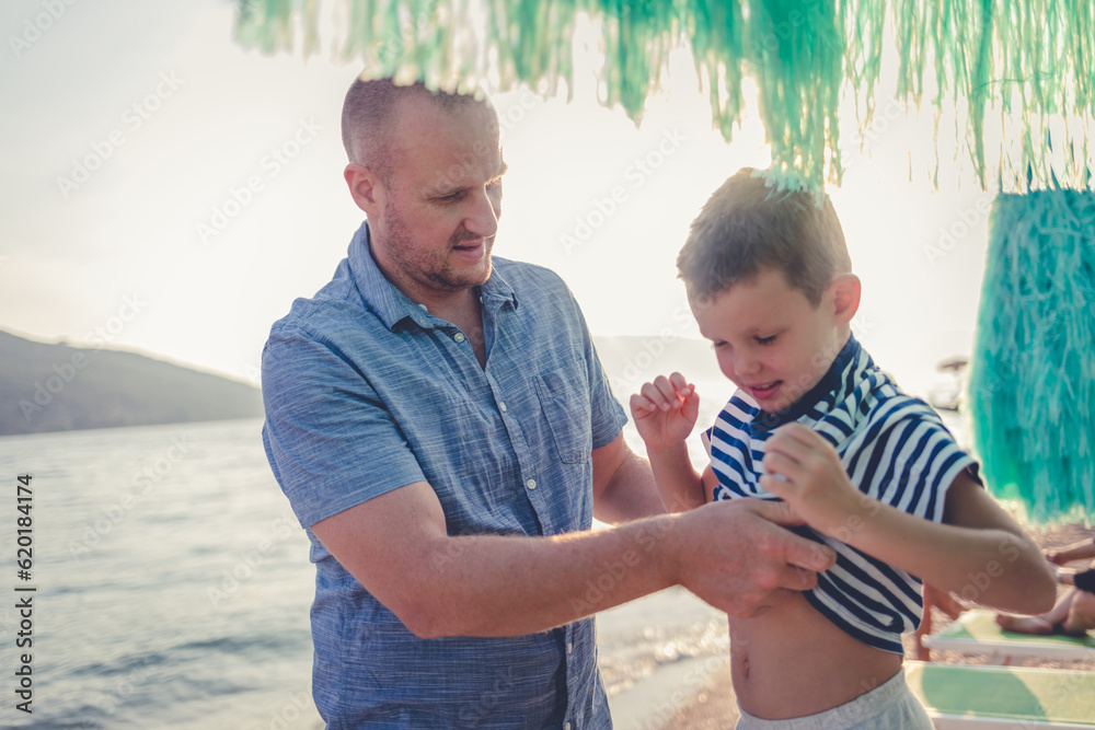 Father helping his son put his clothes on. Father and son having fun on ...