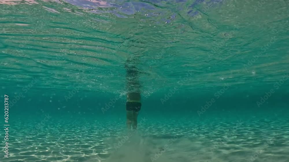 Stockvideon Underwater back view in shallow water of man walking on ...