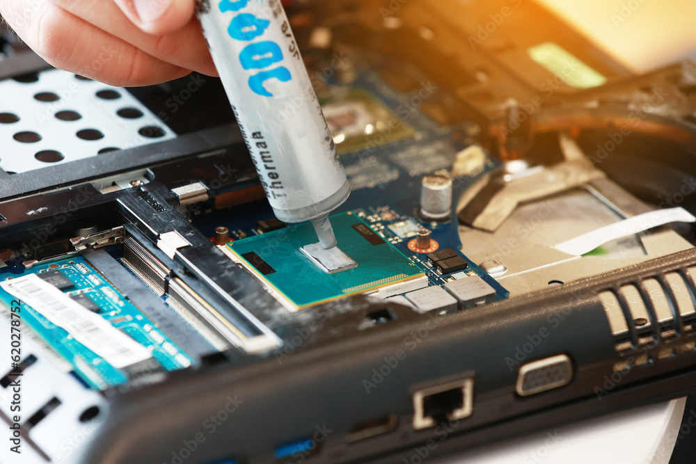 Hand a repairman uses thermal paste syringe apply thermal compound to a CPU. Master replaces ...