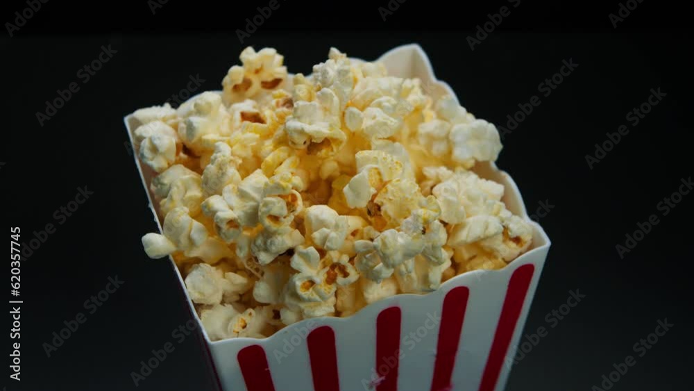 Rotation of air popcorn in a classic box on a black background close-up ...