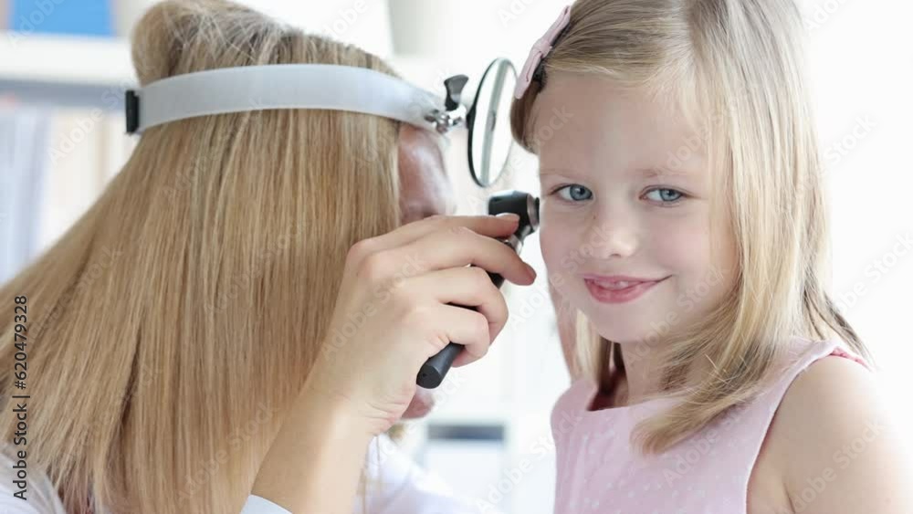 Ent with frontal reflector examining little girl ear with otoscope 4k ...