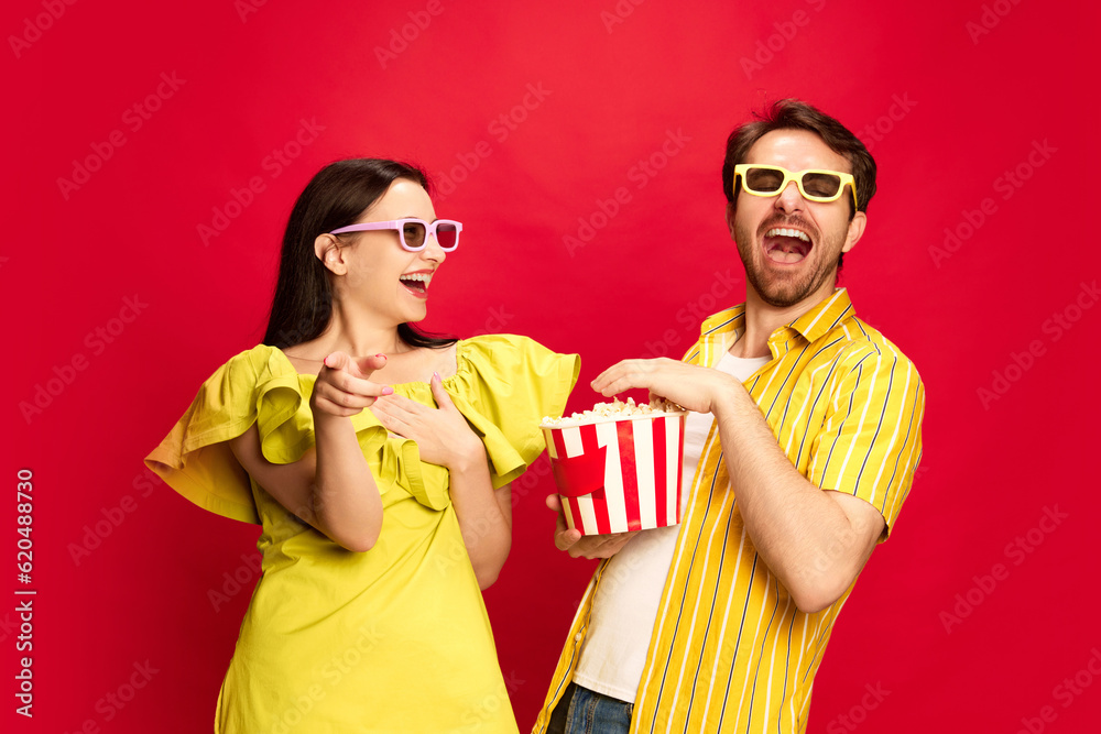 Man and woman emotionally watching movie, eating popcorn against red ...