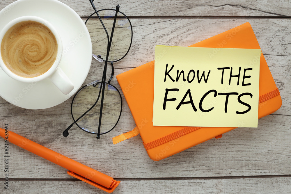know the facts symbol. text on yellow sticky note and desk with orange ...