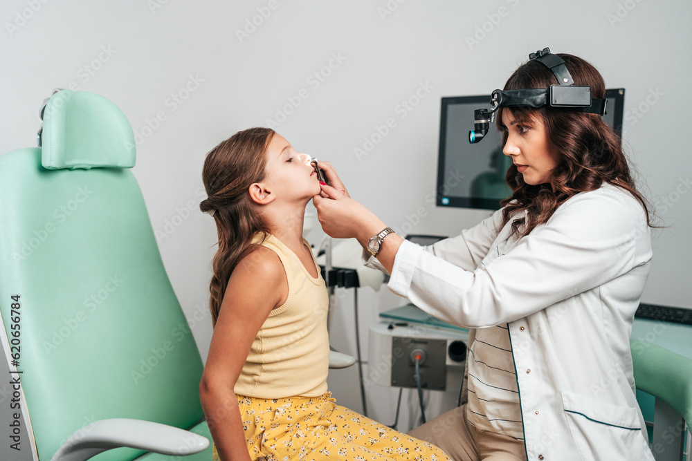 Female audiologist examining girl ear using otoscope in doctors office ...
