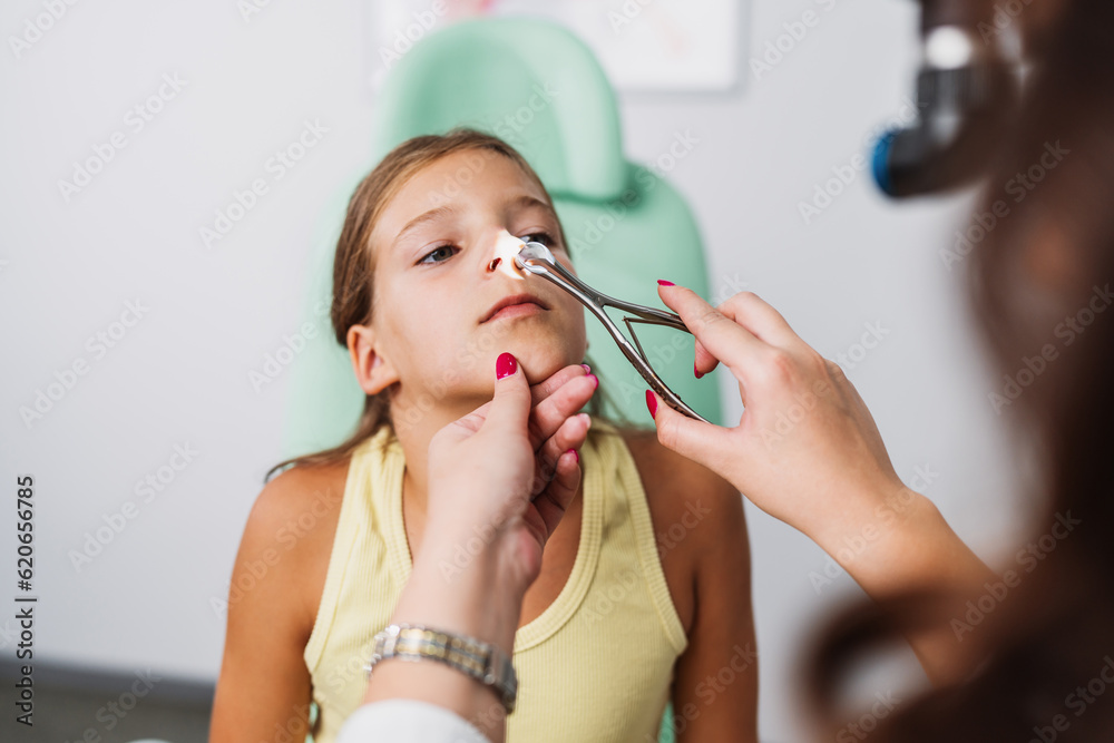 Female audiologist examining girl ear using otoscope in doctors office ...