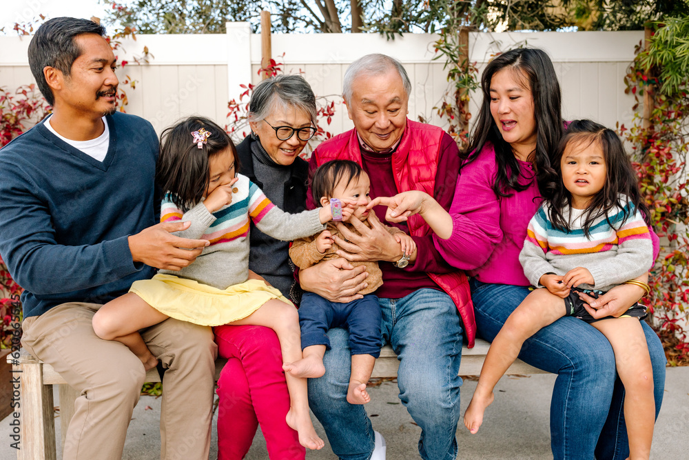 Smiling asian family with grandparents sitting outdoors together Stock ...