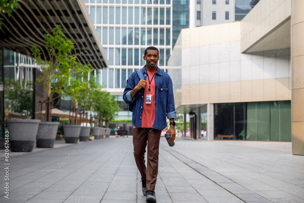 Smiling man carrying backpack on urban city street going to office ...