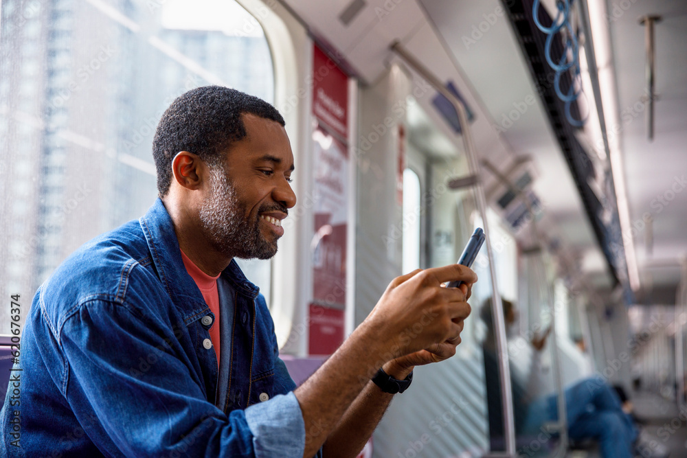 Happy man using mobile phone while traveling in a metro Stock Photo ...
