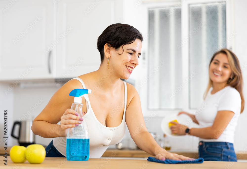 Positive interested young latin american woman with sister cleaning ...