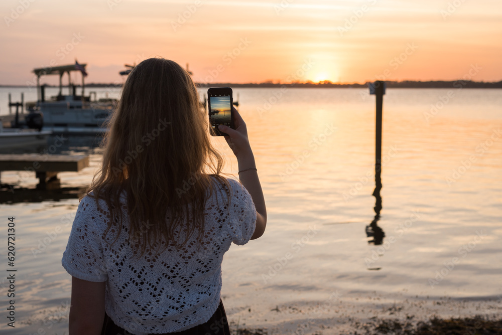Girl taking a sunset photo Stock Photo | Adobe Stock