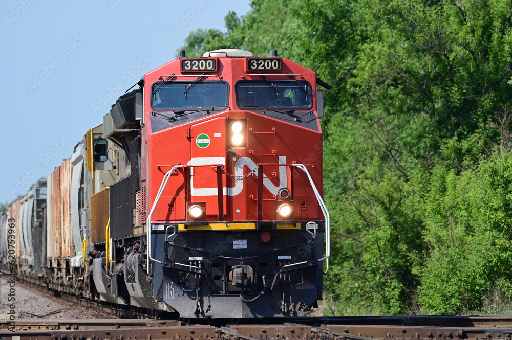 Two locomotives lead a unit freight train over a crossing of the tracks ...