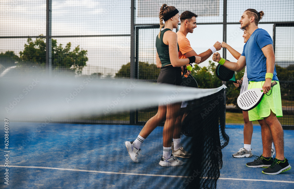 Team celebrating with fist bumps after a doubles padel game Stock Photo ...