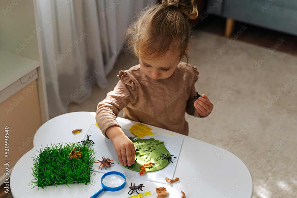 A little girl playing with toy insects. Educational game Bug Fossils ...