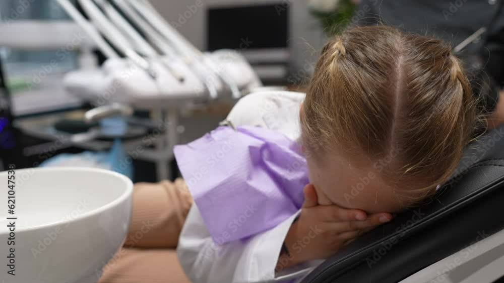 Close-up of scared crying little child girl sitting in dental chair ...