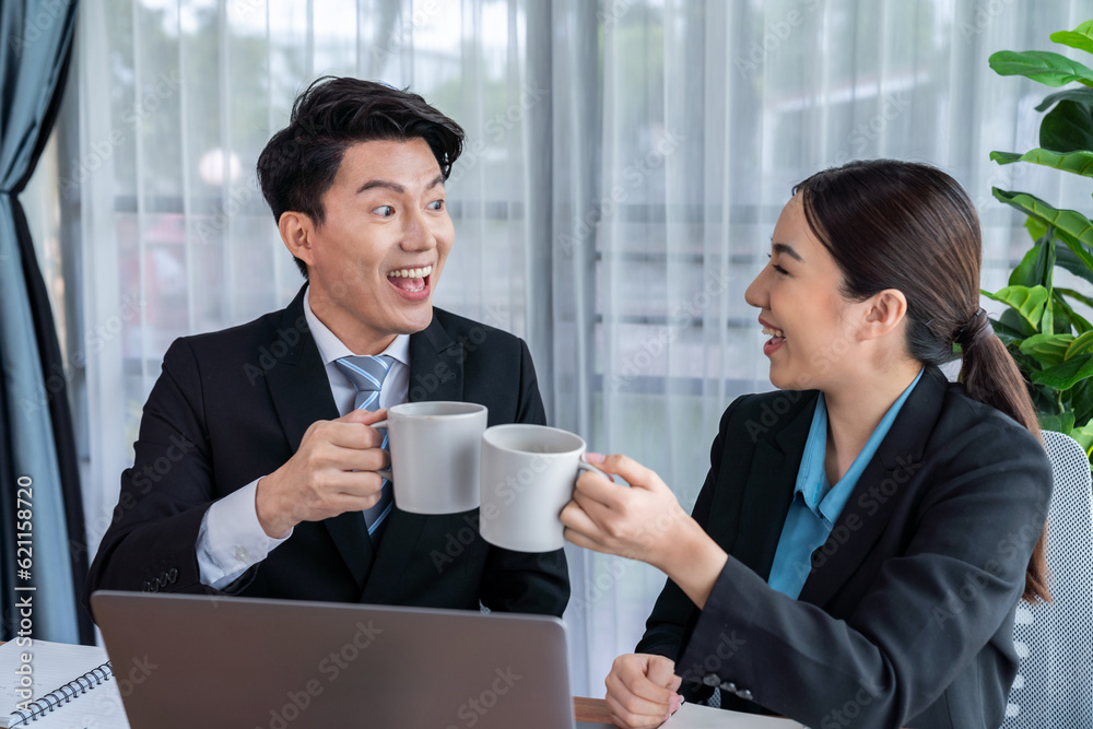 Two Asian office workers taking coffee break together in workplace ...