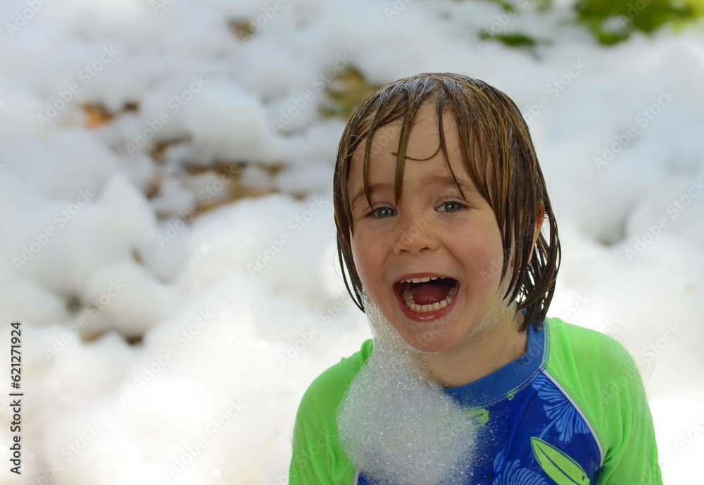 Funny little boy covered in soapy foam. Kids having fun at a soap foam ...