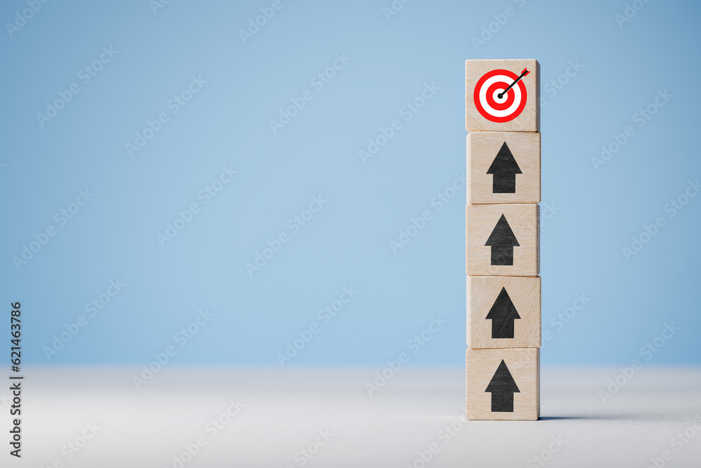 wooden block with target aiming dart board and arrow up on blue ...