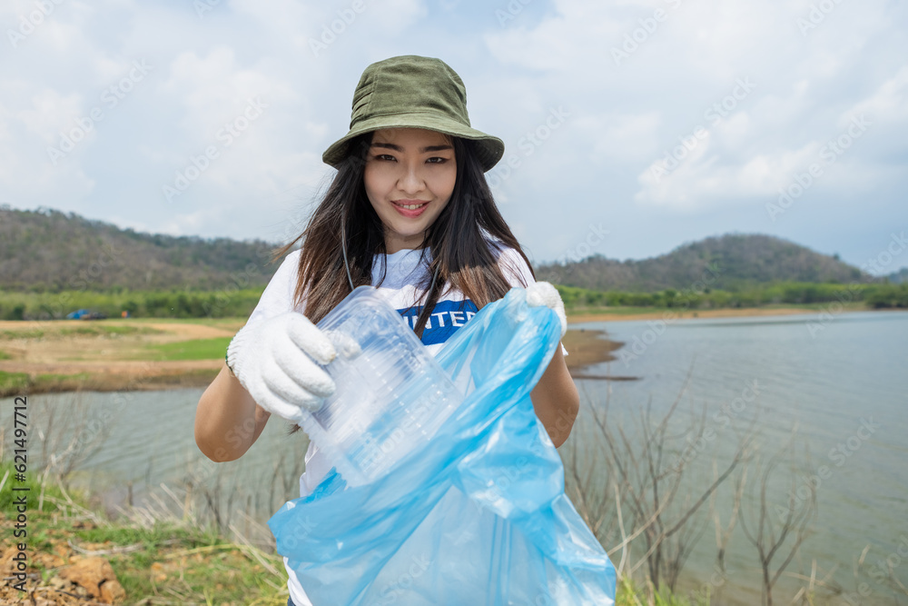 Female volunteers holding plastic box put in garbage bag, conducting ...