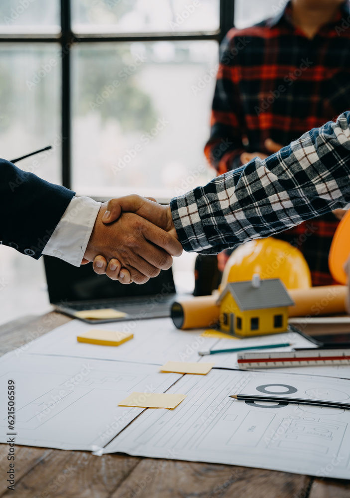Construction workers, architects and engineers shake hands while ...