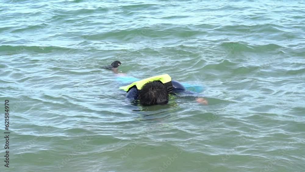 Asian men wear a life jacket floating in the sea It's about to close to ...
