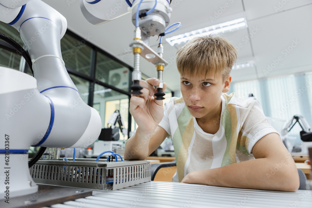 Boy caucasian education electronic robotic arm on table at class room ...