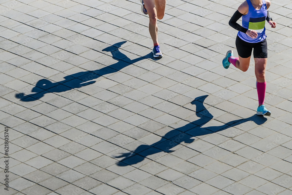 overhead view two female athletes running marathon race, shadows of ...