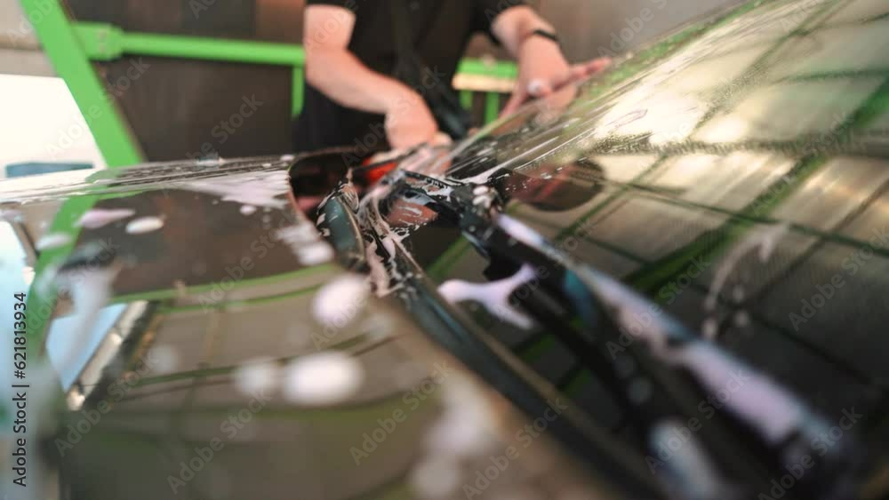 Male driver washing his windshield with nano foam with wipers while ...