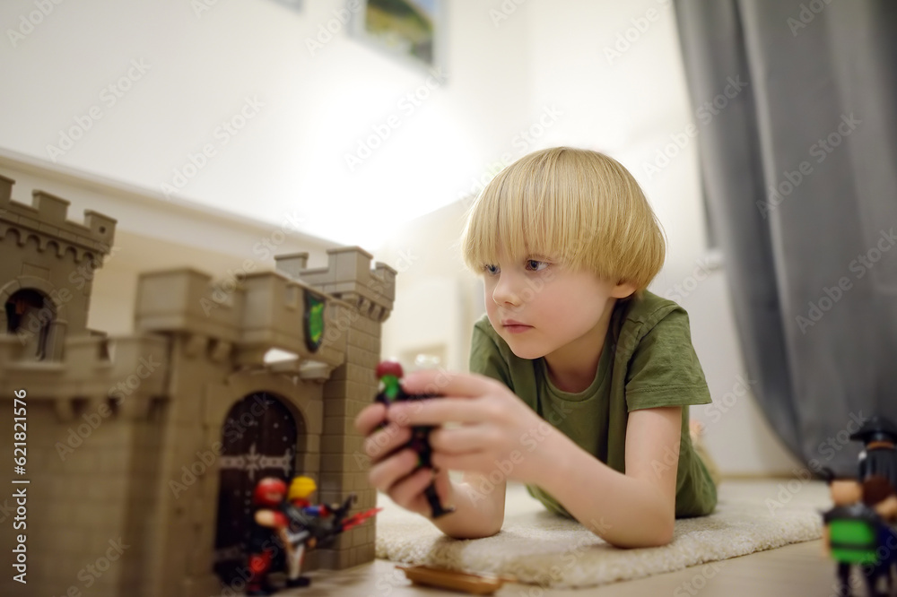 Little child is playing with toy prototype Medieval Castle. Knights and ...