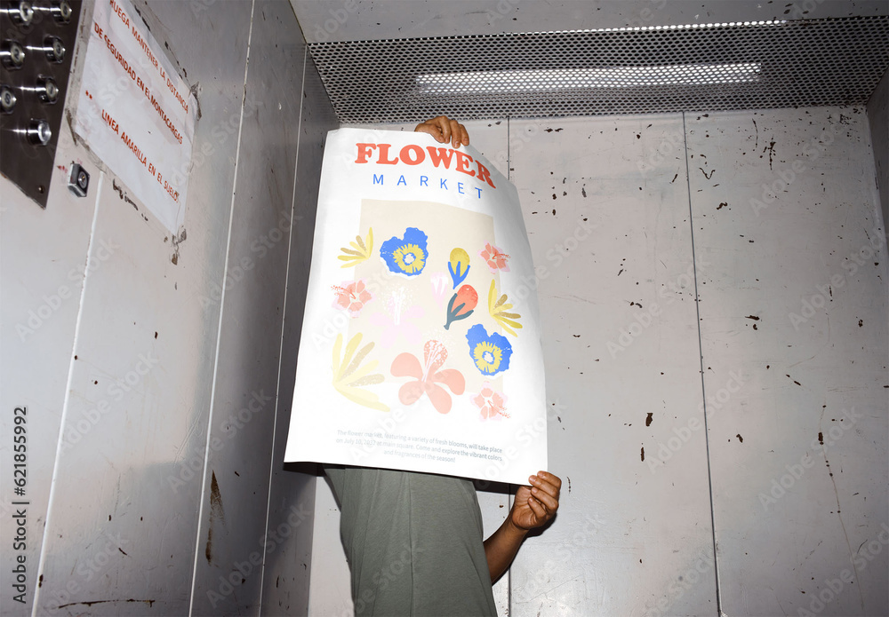 Mockup of woman in elevator holding customizable A2 poster in front of ...