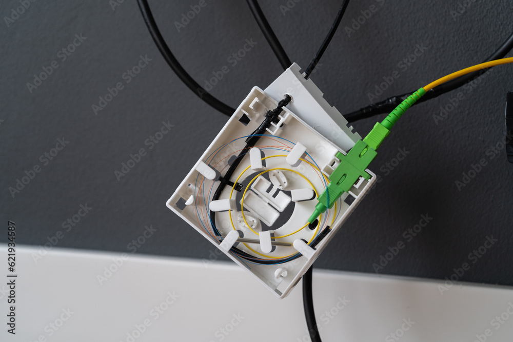 Installation of fiber optic cable in a box on the wall at home. High ...