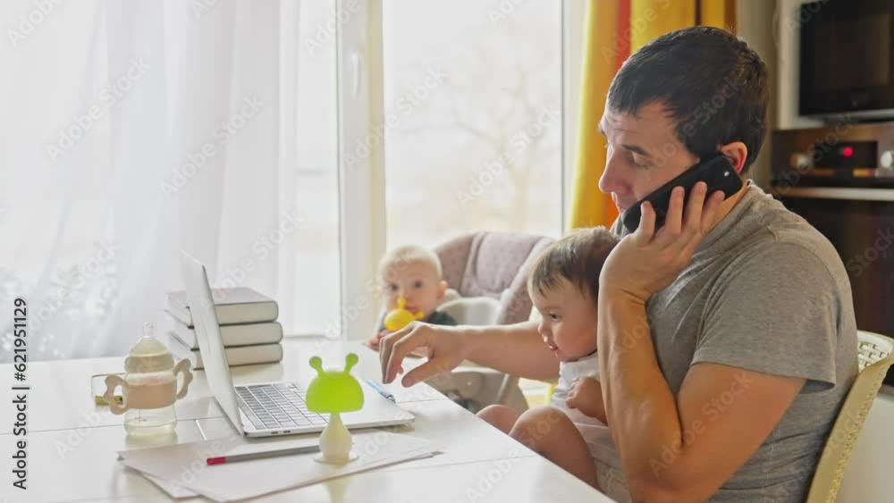 father working from home remotely with baby daughter in his arms ...