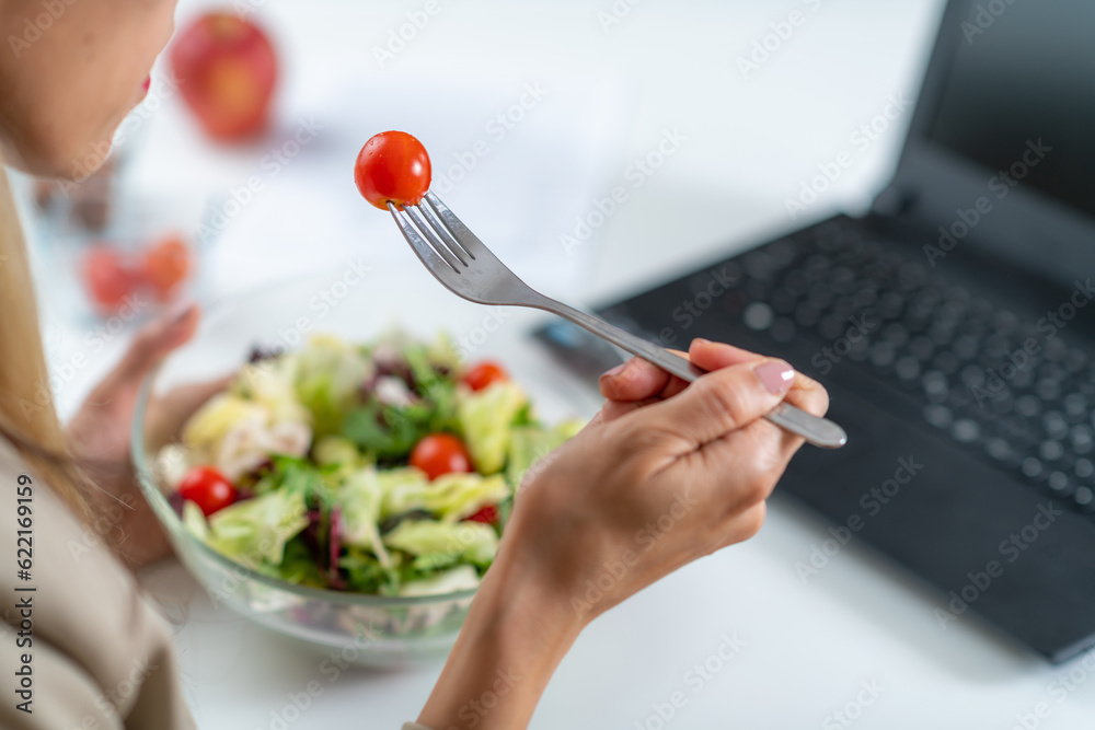 Foto de Healthy eating at work. Woman indulges in a delightful fresh ...