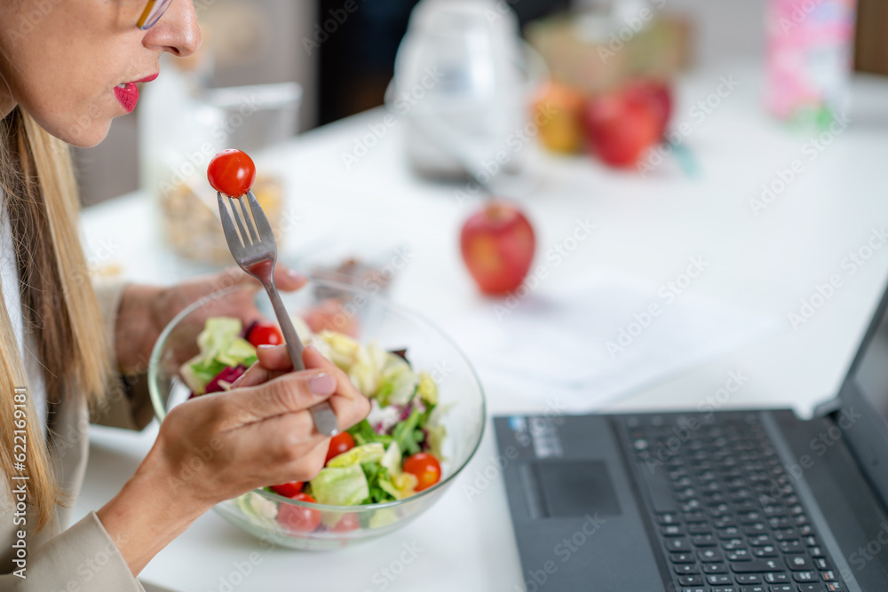 Foto de Healthy eating at work. Woman indulges in a delightful fresh ...